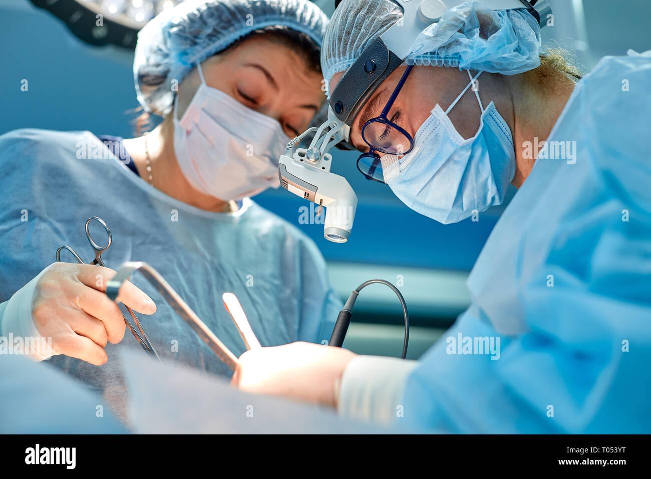 Portrait of professional surgeons during surgery on a blue background ...