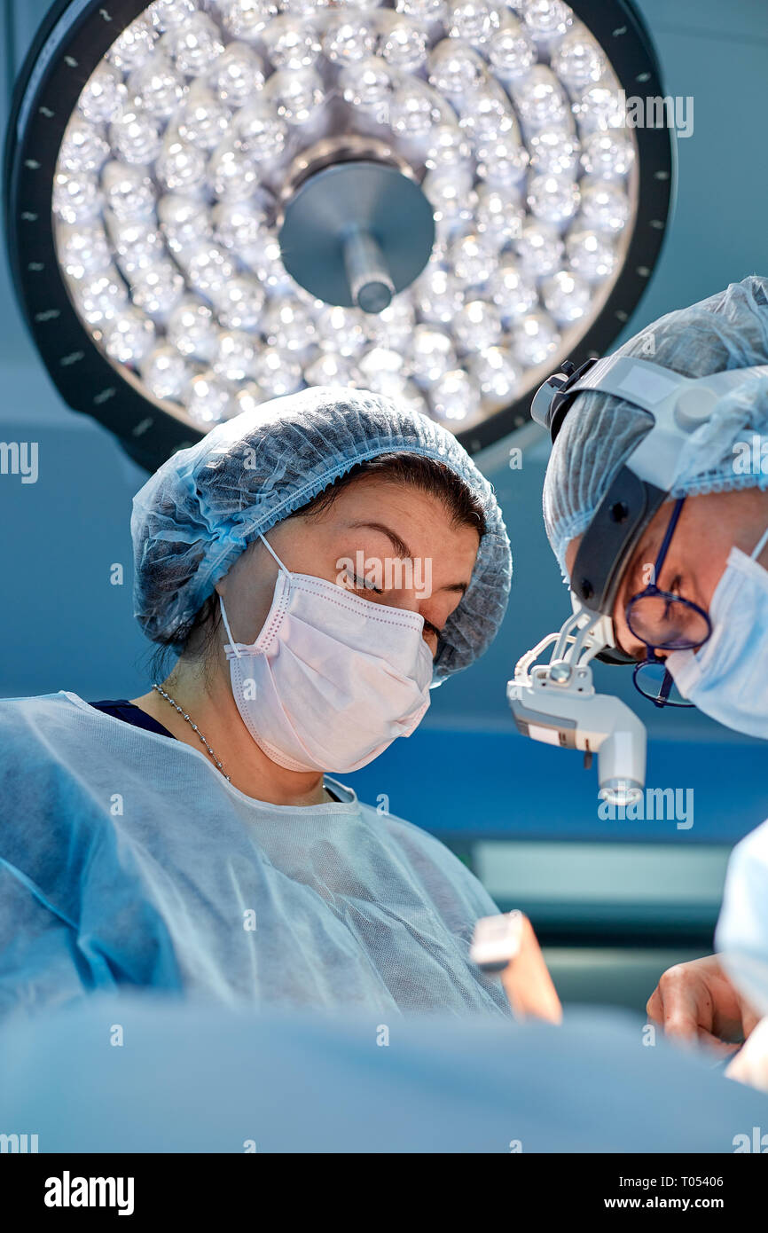 Portrait of professional surgeons during surgery on a blue background ...