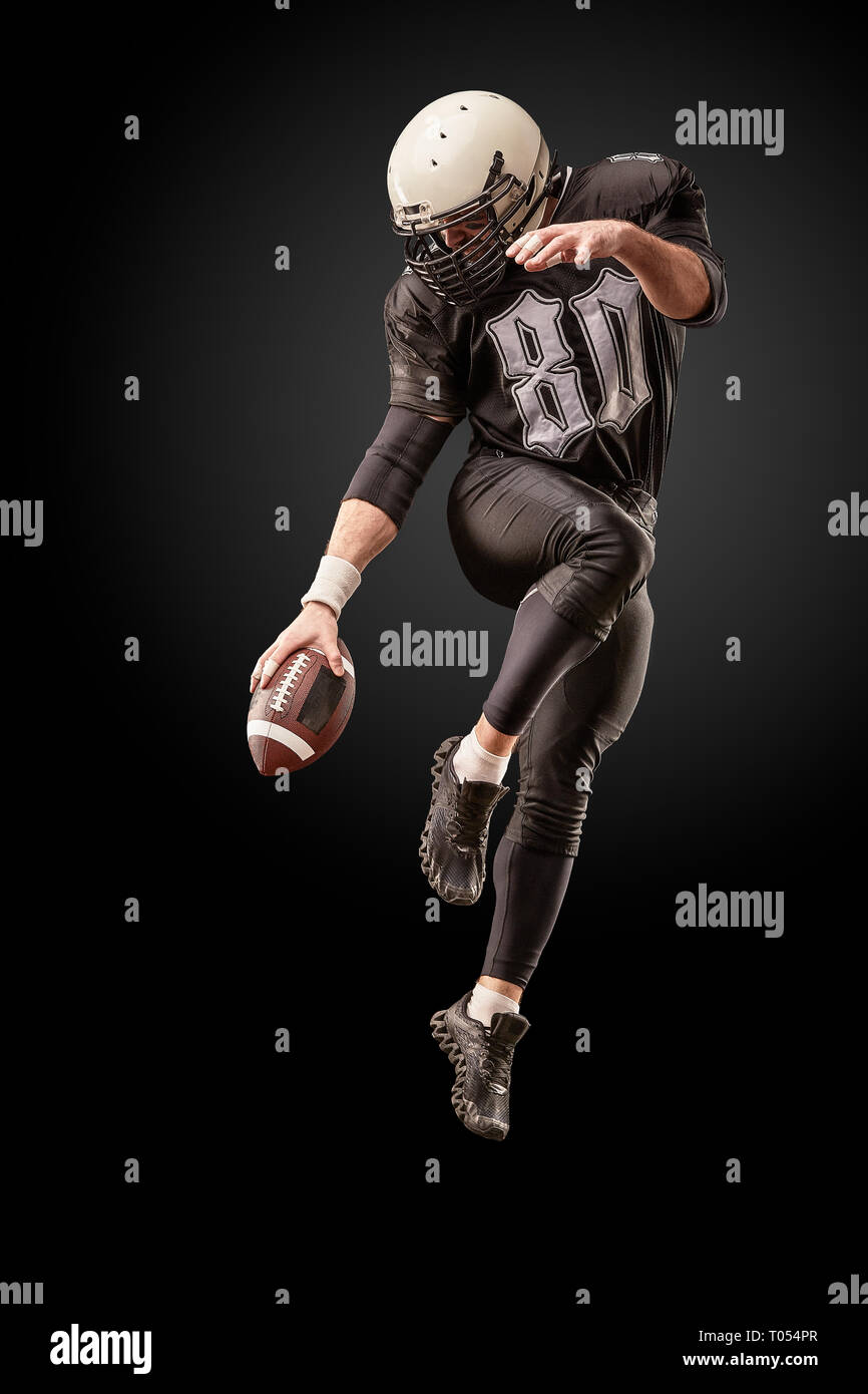 American football player in a jump with a ball on a black background ...