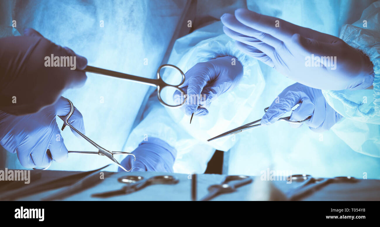 Surgeons hands holding surgical scissors and passing surgical equipment ...