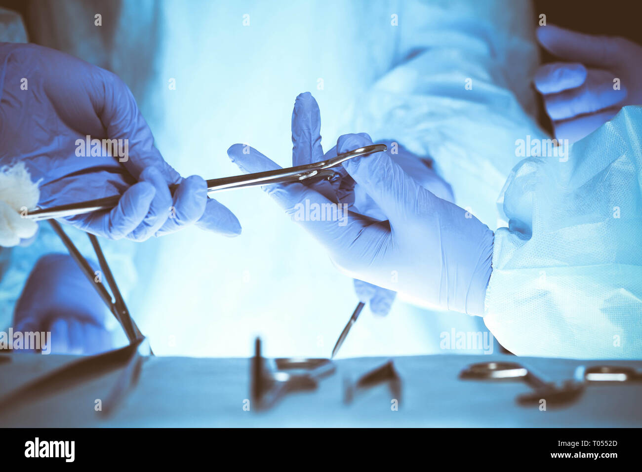 Surgeons hands holding surgical scissors and passing surgical equipment ...