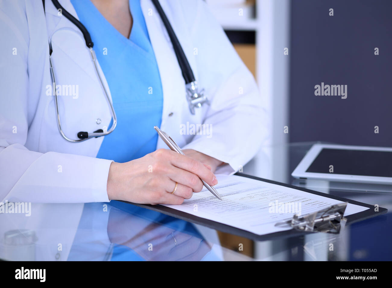 Female doctor filling up medical form on a clipboard, closeup ...