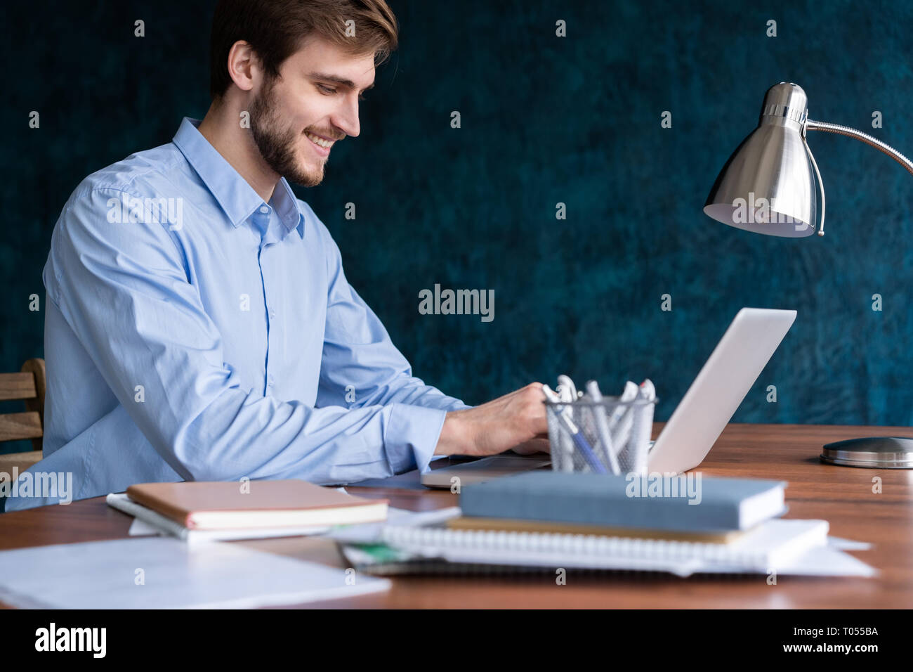 Happy young businessman using laptop at his office desk Stock Photo - Alamy