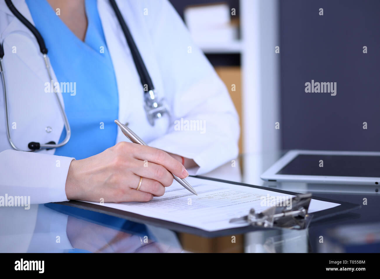 Female doctor filling up medical form on a clipboard, closeup ...