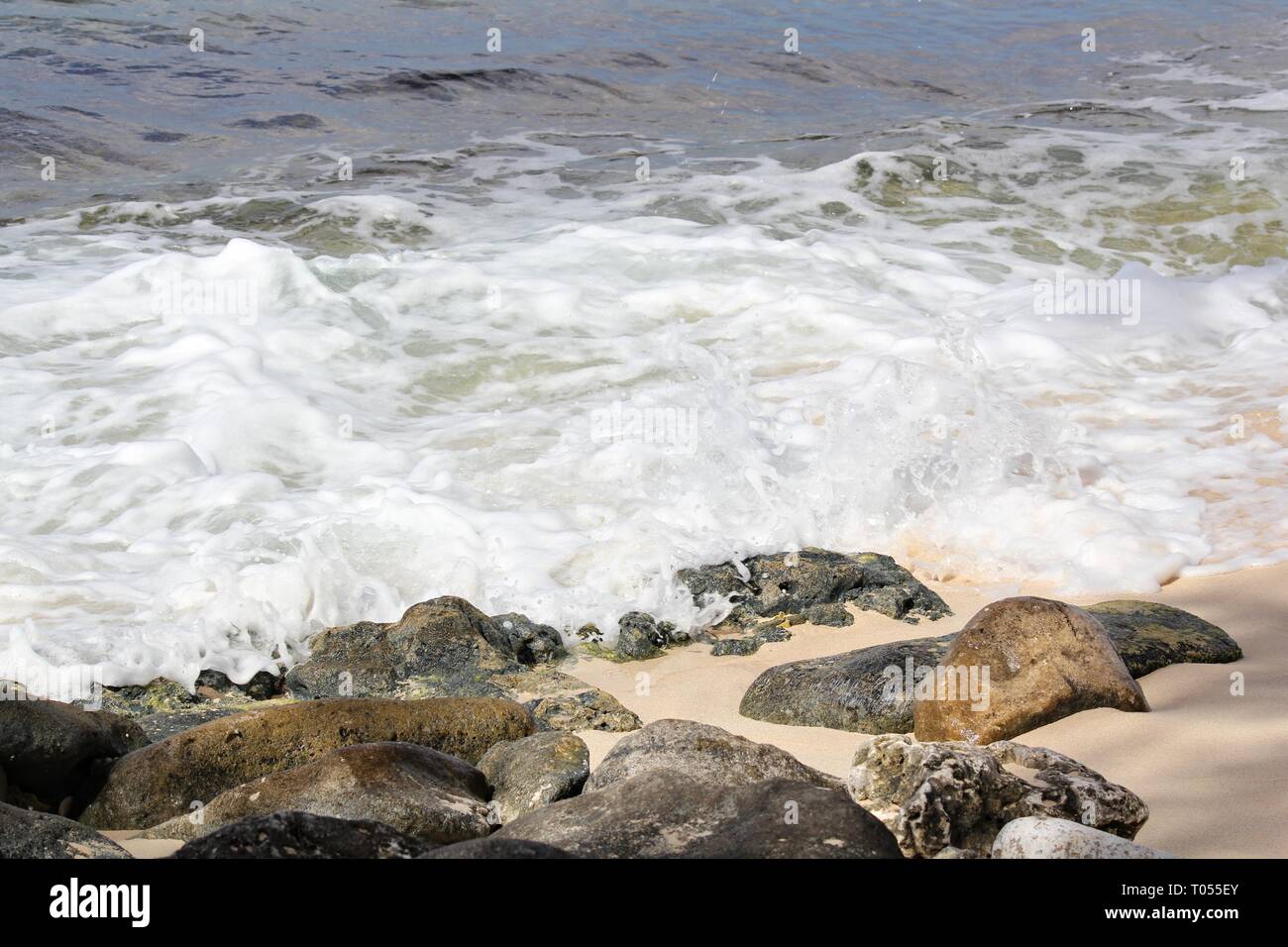 Beautiful foaming waves breaking up on a white sandy beach with rocks ...