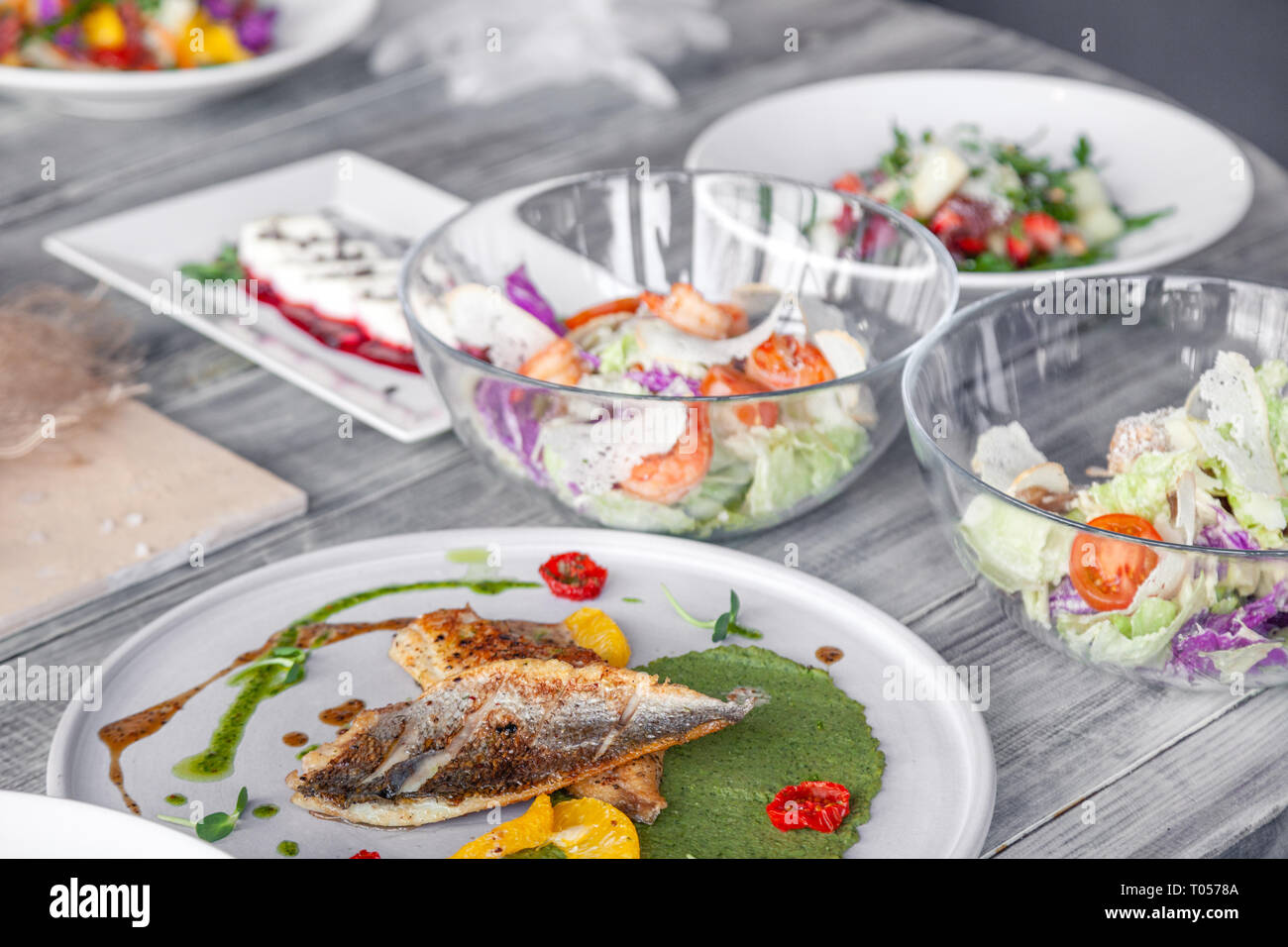 Many different dishes, fish, salads served on the restaurant table ...