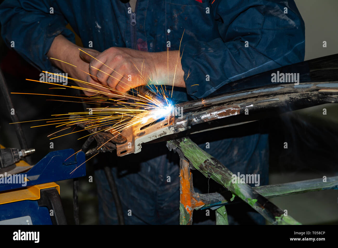 Close-up view strong man is a welder in blue working overalls without ...
