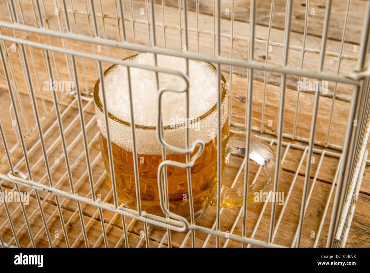 Glass of beer inside a cage, a concept on alcohol addiction and abuse ...