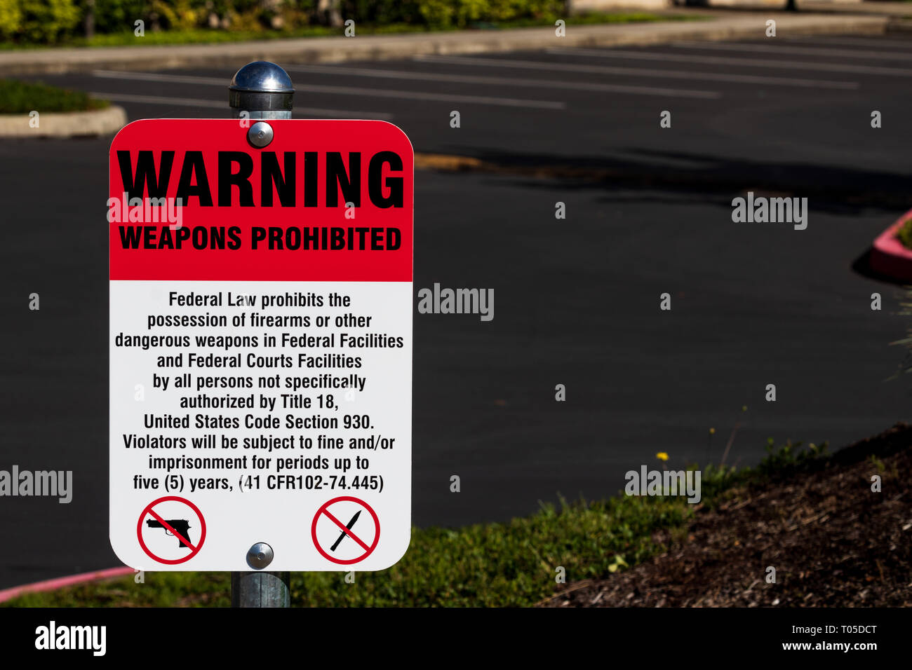 Warning weapons prohibited sign in front of a parking lot in daylight ...