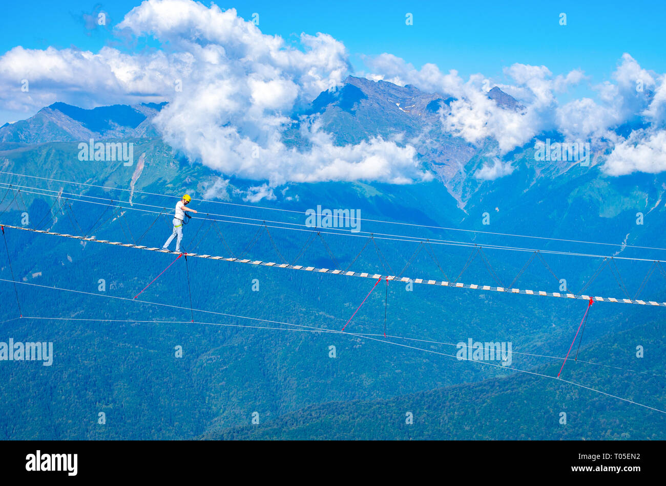 Photo of a man walking on a cable car over an abyss in the mountains ...