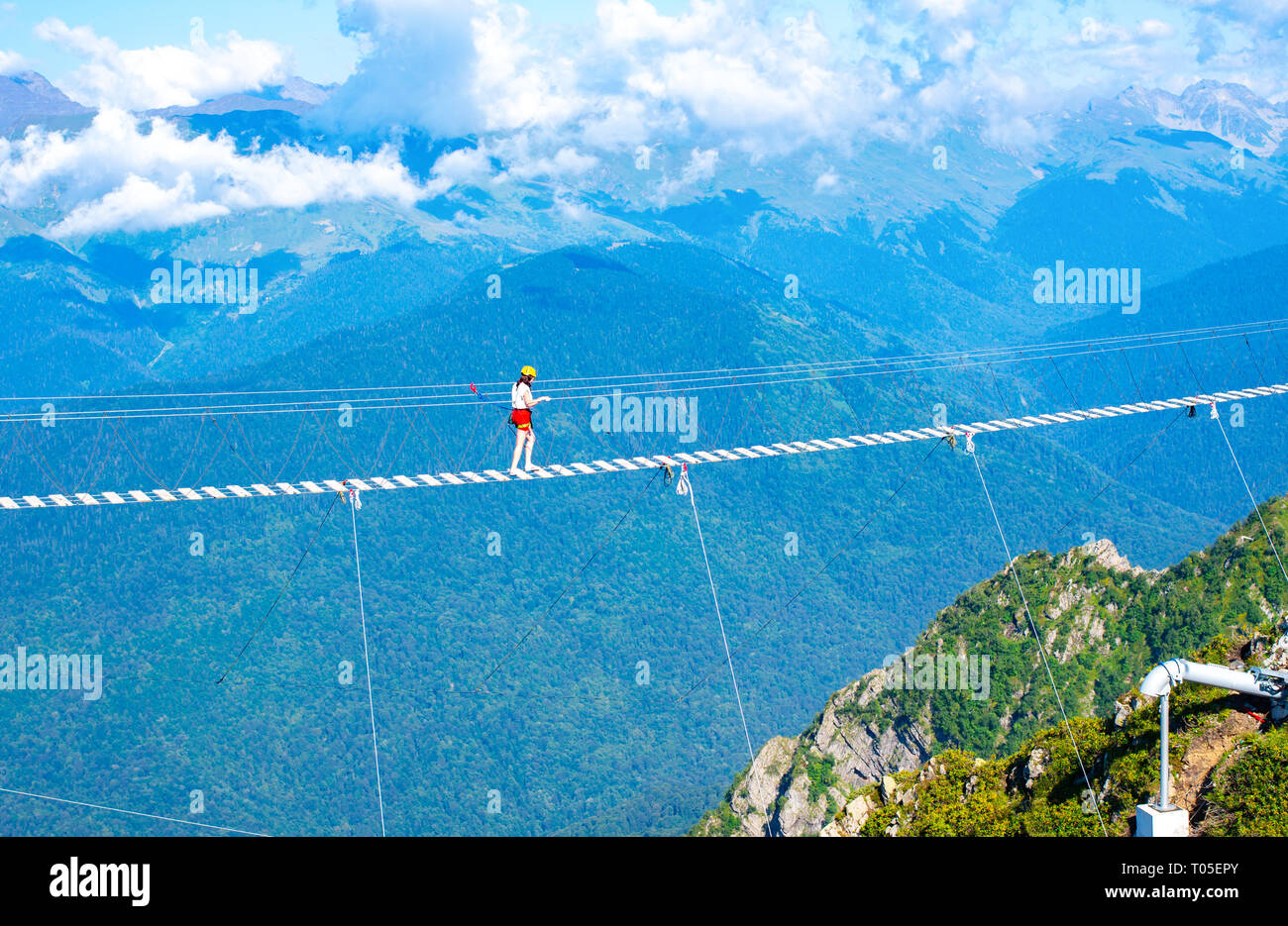 Photo of a man walking on a cable car over an abyss in the mountains ...