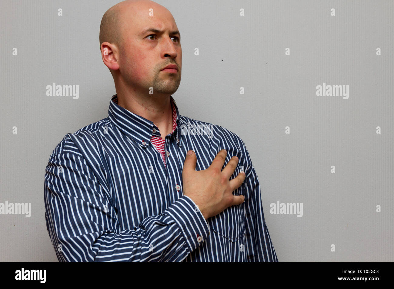 Young guy with his hand on his chest on a gray background Stock Photo ...