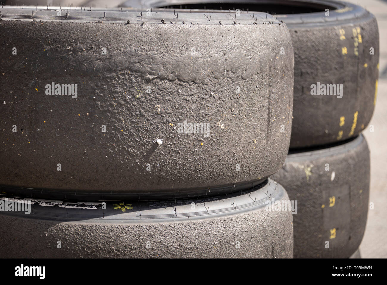 A stack of motorsport racing tires showing road debris, horizontal ...