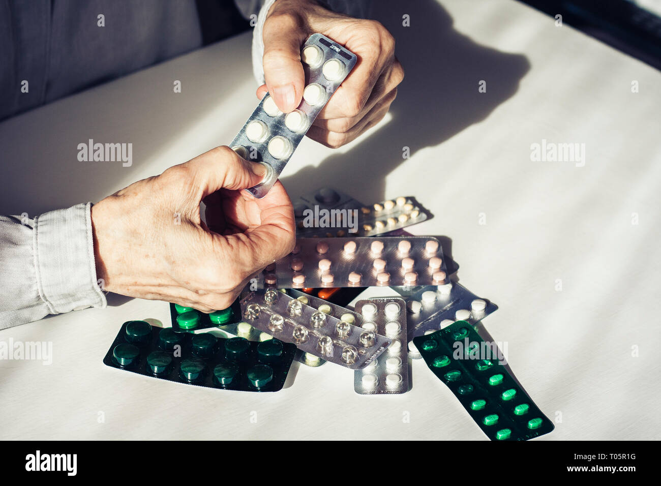 Medicine pills or capsules with old woman’s hands on white background ...