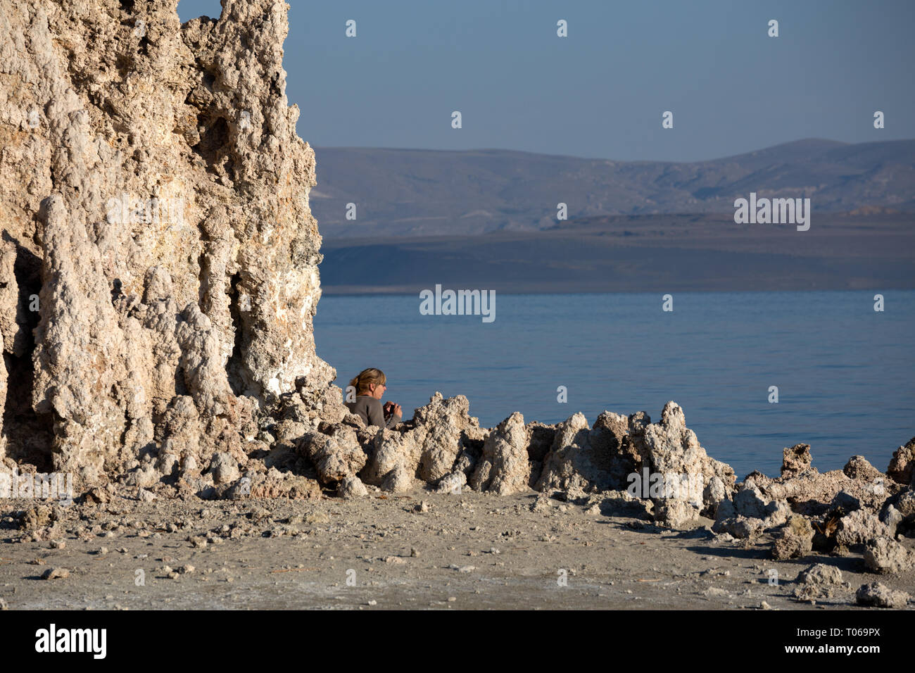 An adult female waiting to take a photograph amongst the tufa towers in ...