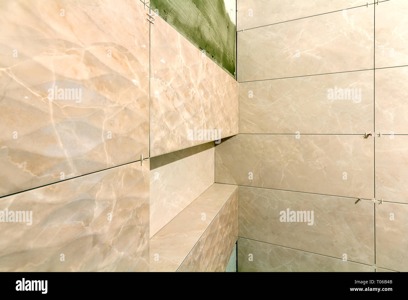 Unfinished work, light beige ceramic tiles installed on walls of ...