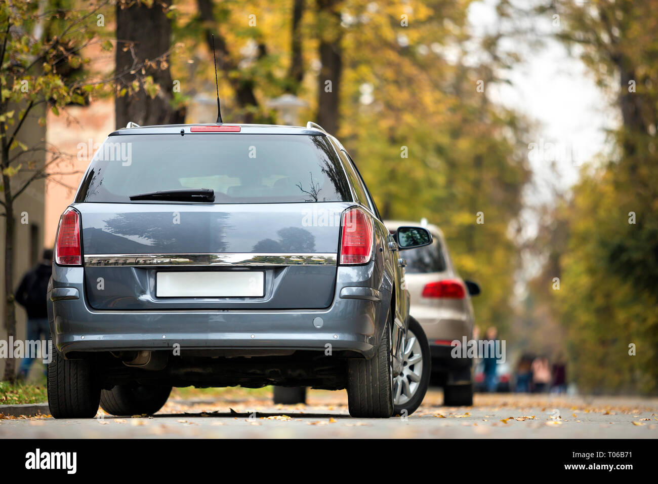 Gray shiny car parked in quiet area on asphalt road on blurred bokeh ...