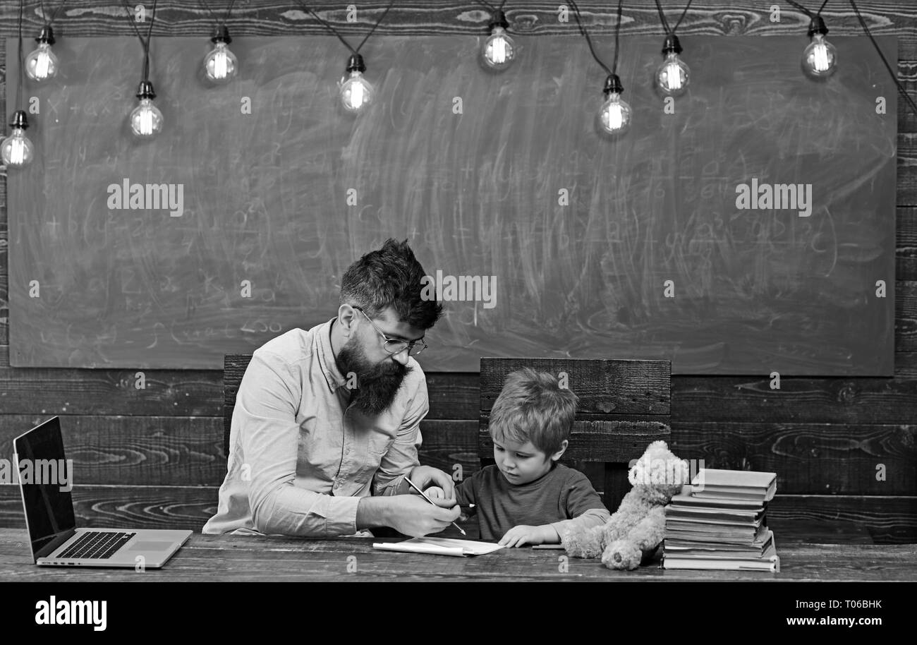 Pupil with teacher at school. Tutor helping kid to write letters in ...