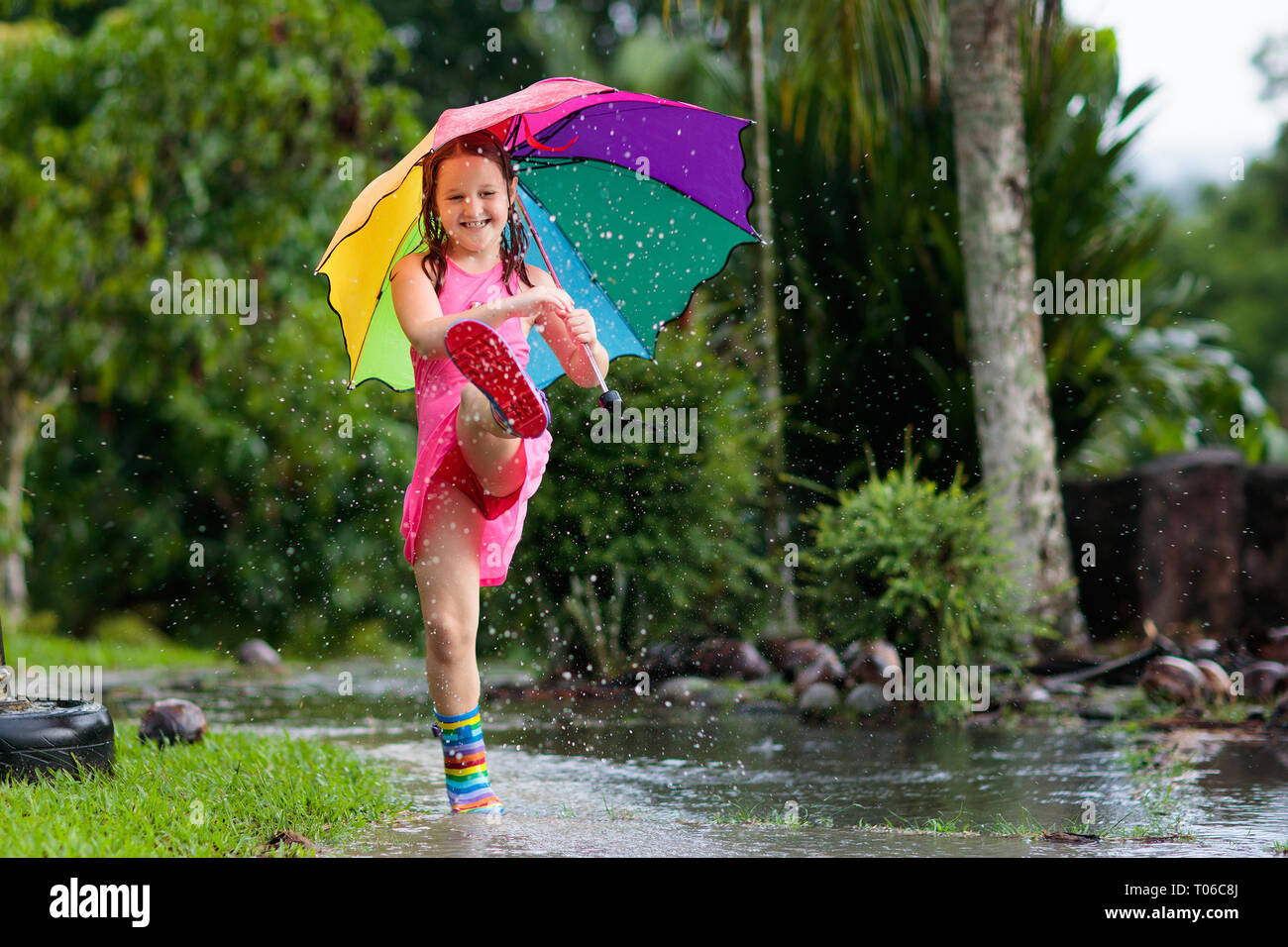 Kid playing out in the rain. Children with umbrella and rain boots play ...