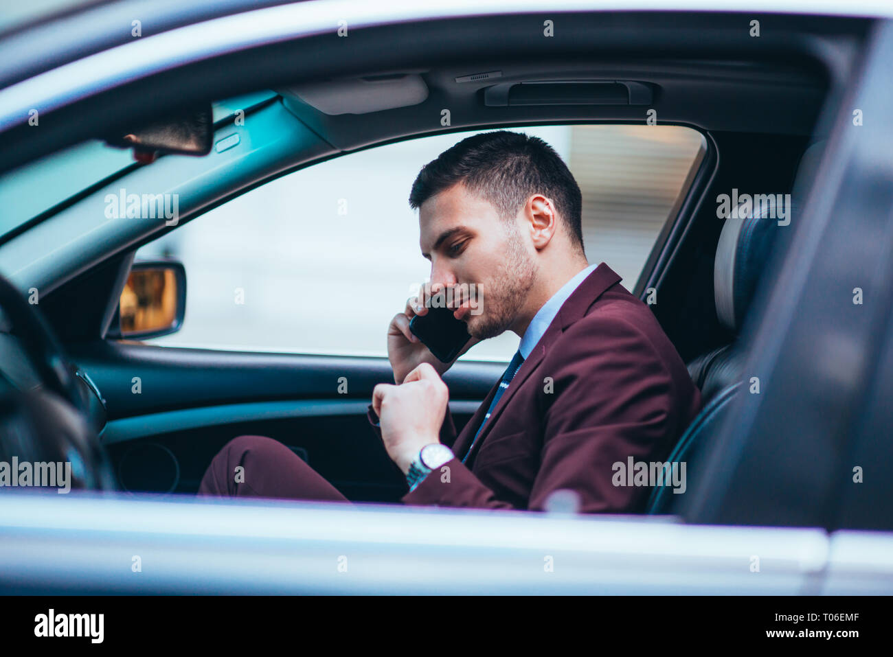 A manager sitting at the front seat of his limo talking on his ...