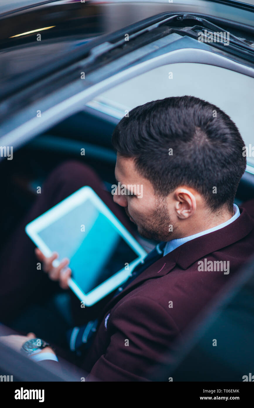 Above head perspective of a businessman working on his tablet while ...