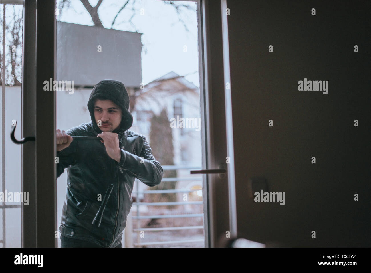 Housebreaker wearing black clothes and leather coat breaking in a house ...