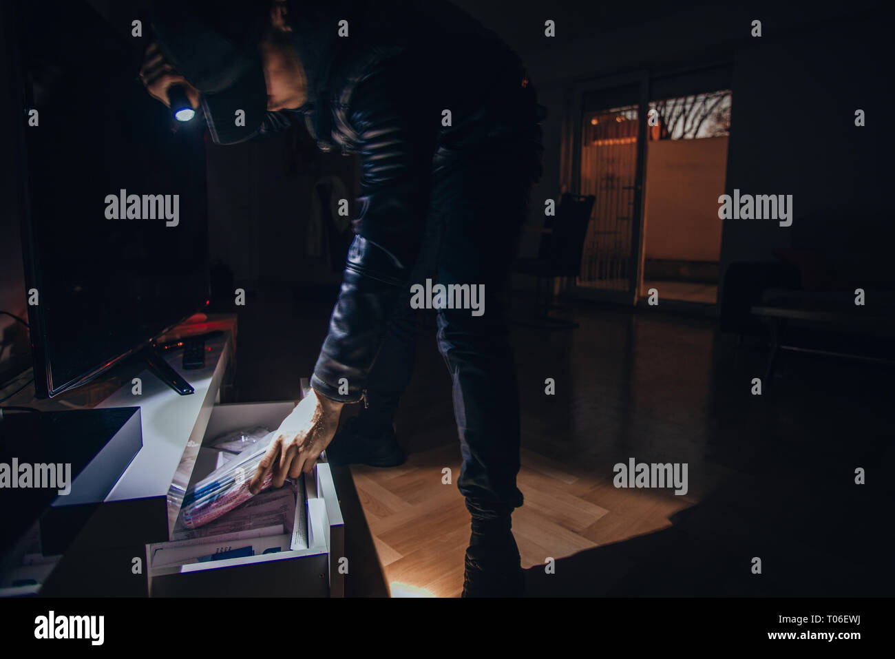 Adult thief wearing black looting from the desk in living room Stock ...
