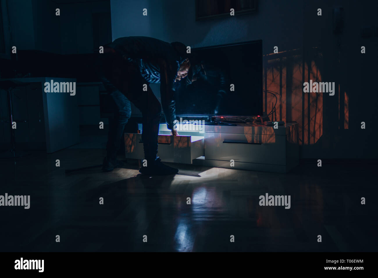 Young thief walk in the apartment and stealing from the desk Stock ...