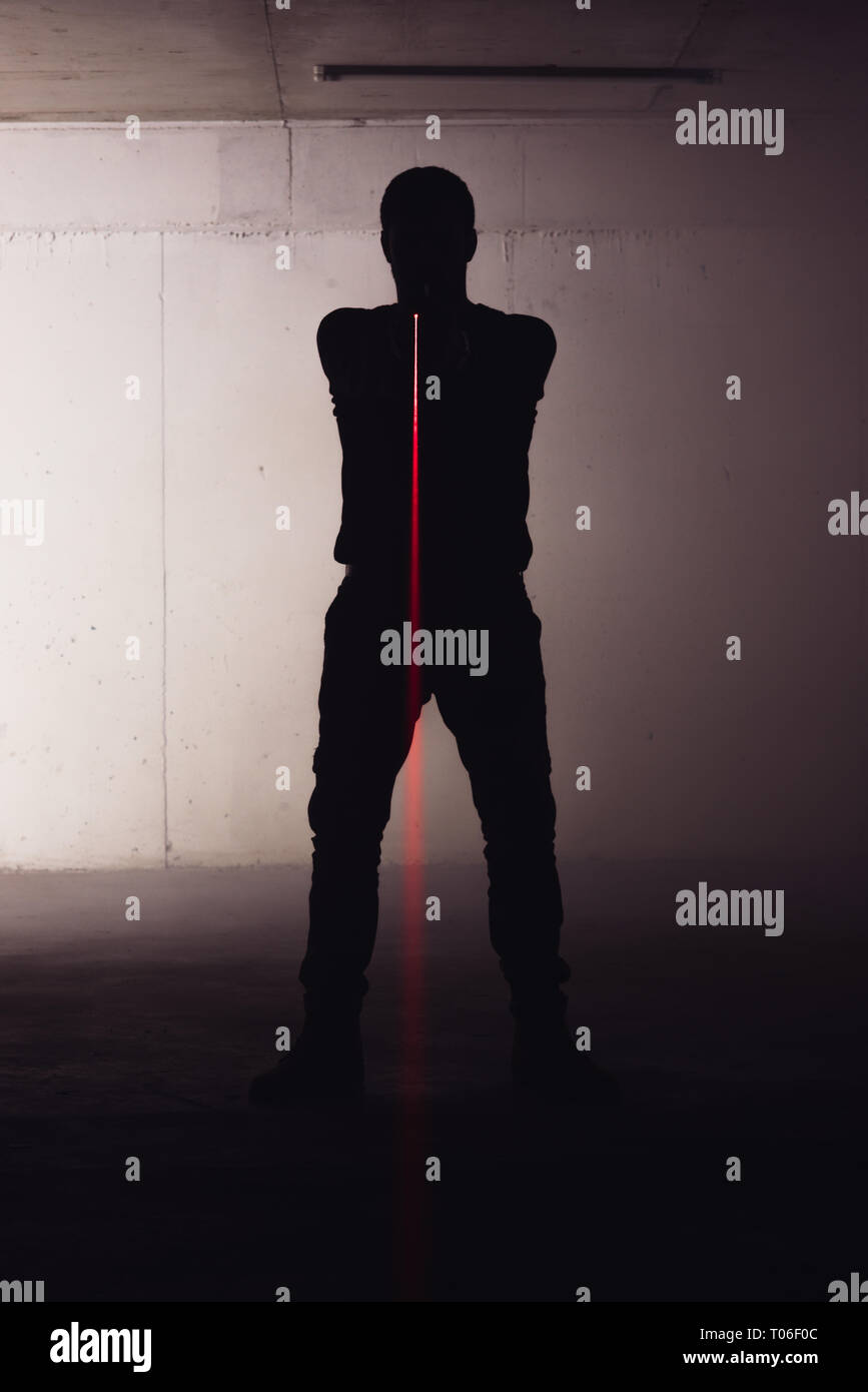 silhouette of an armed man holding his gun and pointing with his laser ...