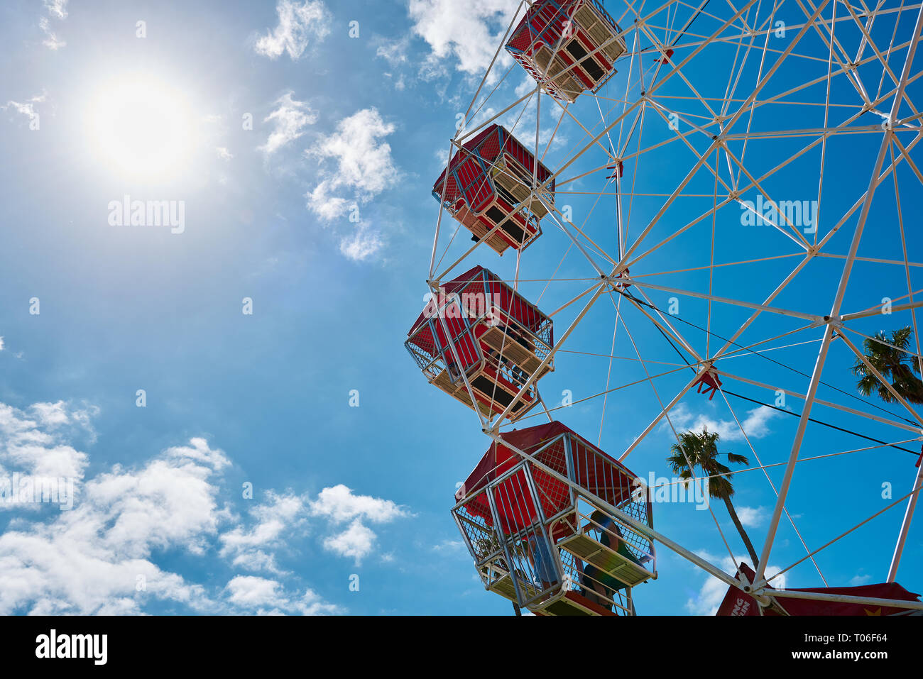 Close view of a colorful Ferris wheel against a vibrant blue sky and ...
