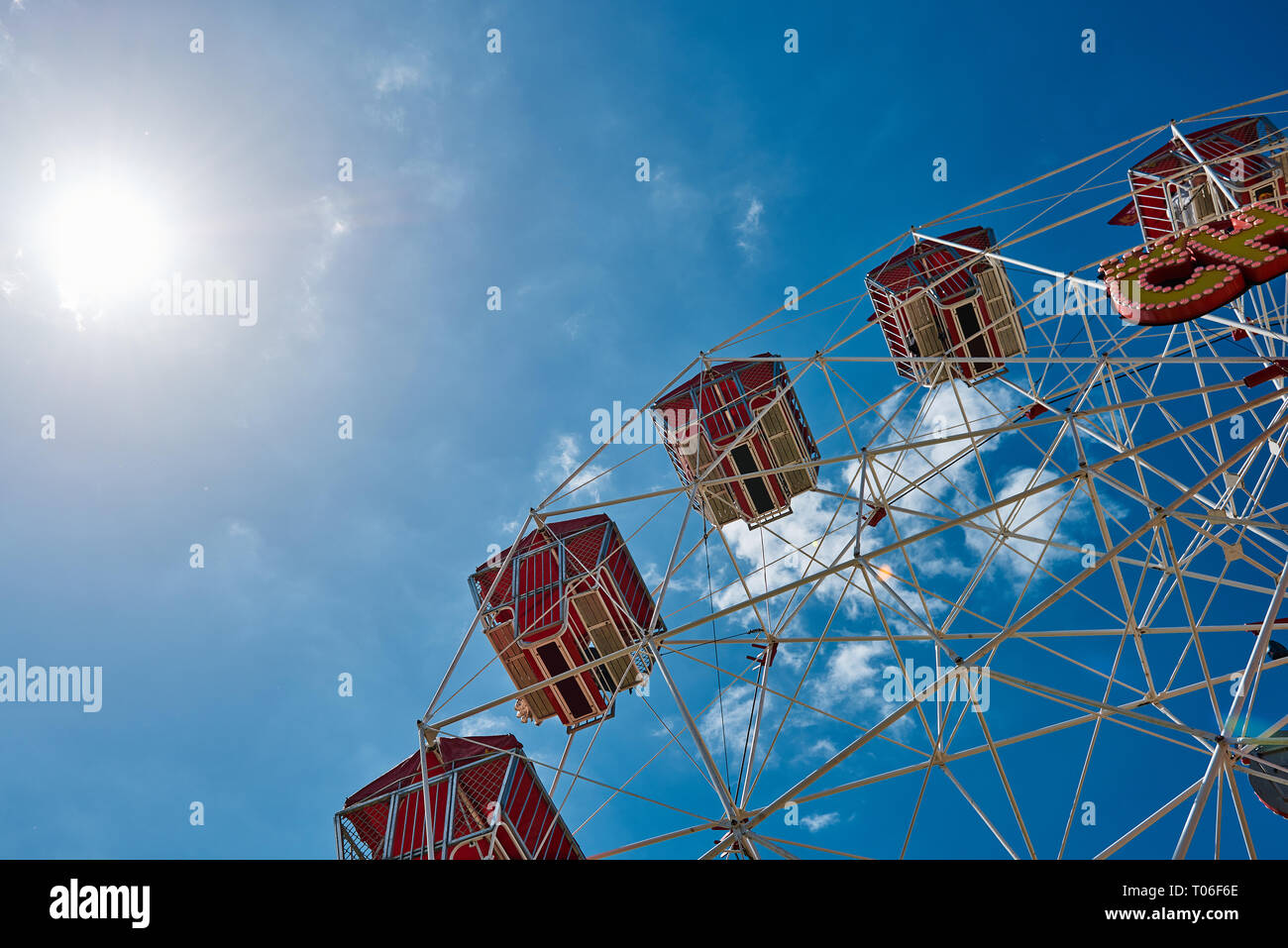 Red Ferris wheel pictured from below against a blue vibrant sky with ...
