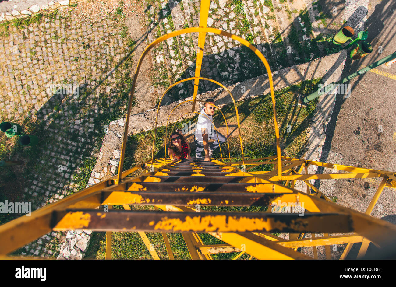Young friends are having fun while climbing metal ladder looking up on ...