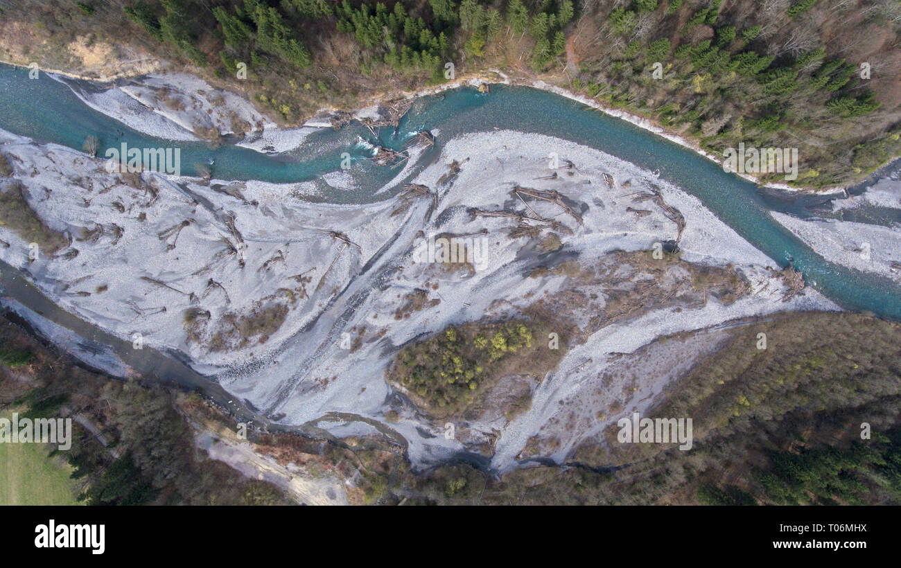 Overhead drone view of a fast flowing alpine melt river in a pine ...