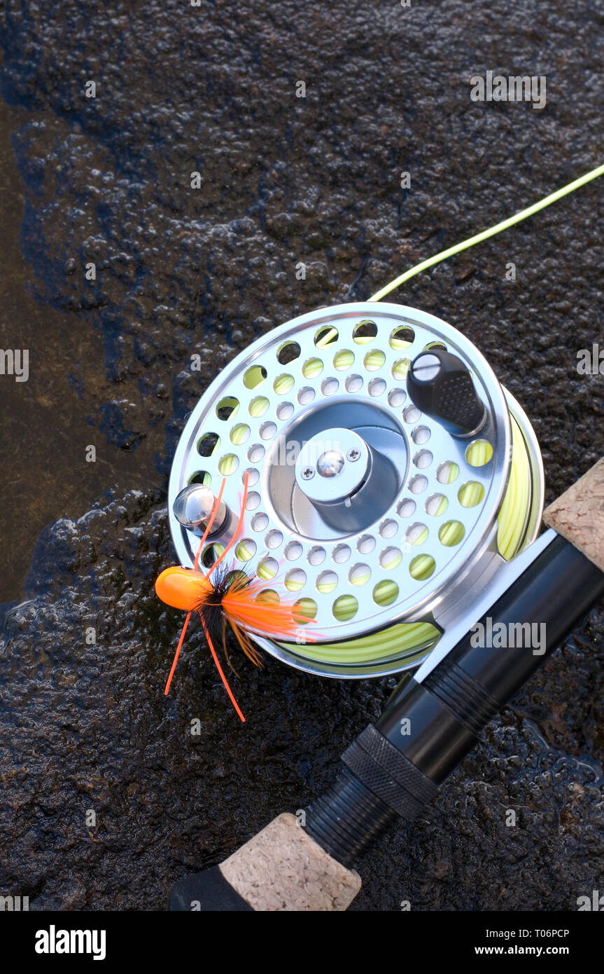 Fly fishing Rod and Reel with Orange Spider Lure on Wet Rocks Stock ...