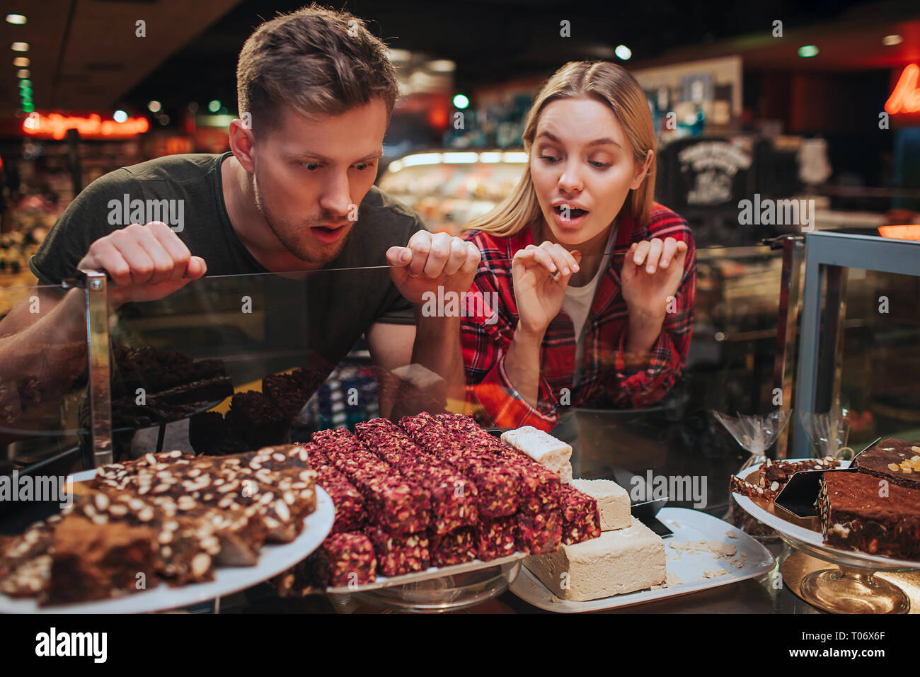 Young couple in grocery store. Hungry man and woman look at sweets on ...