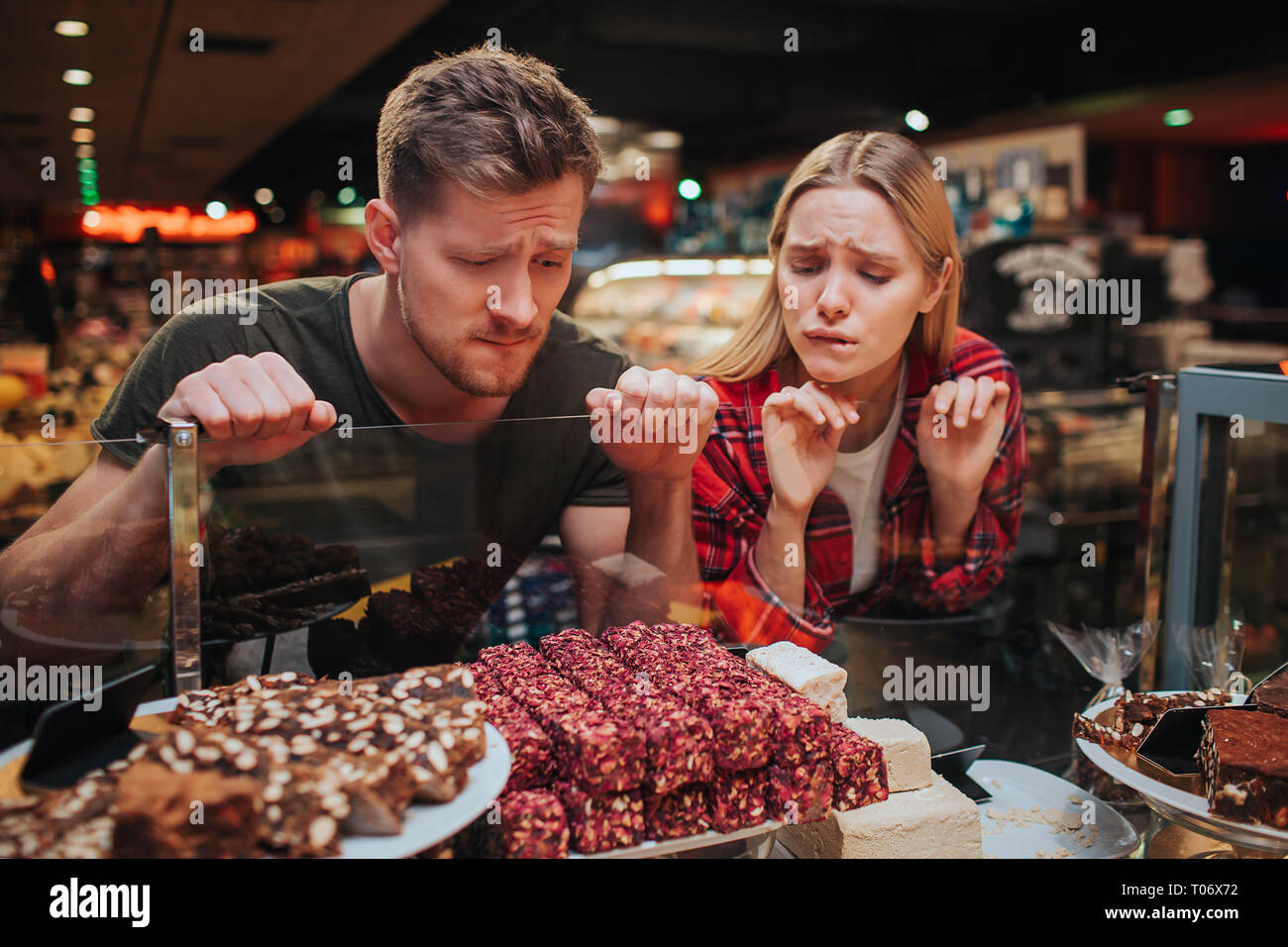 Young couple in grocery store. They look at sweets with hunger and ...