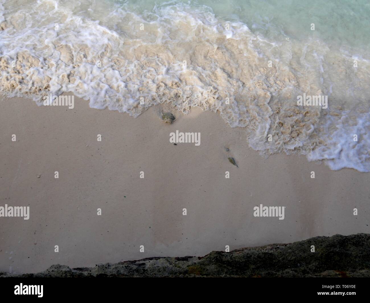 Small foaming waves gently pulling back to the ocean against the soft ...