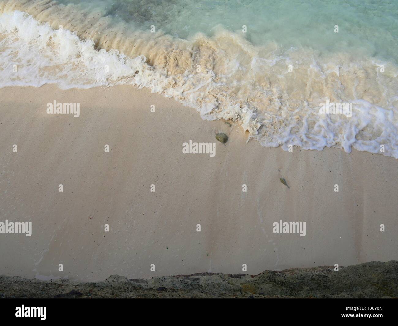 Foaming waves gently pulling back to the ocean in a continuous pattern ...