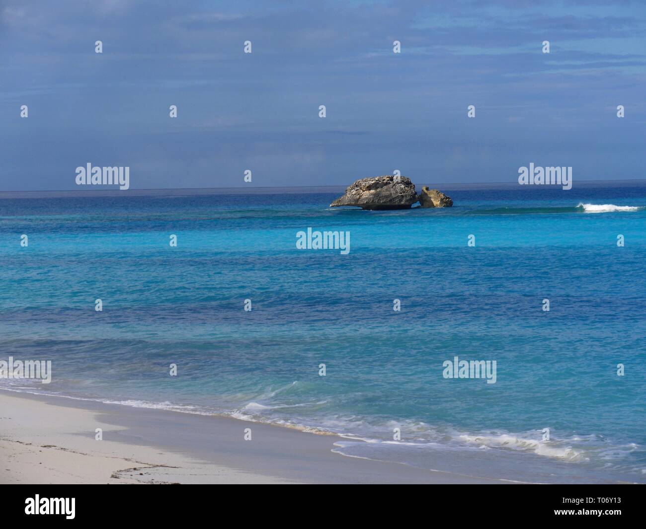 A beautiful rock formation breaks the vast blue of the waters in a ...