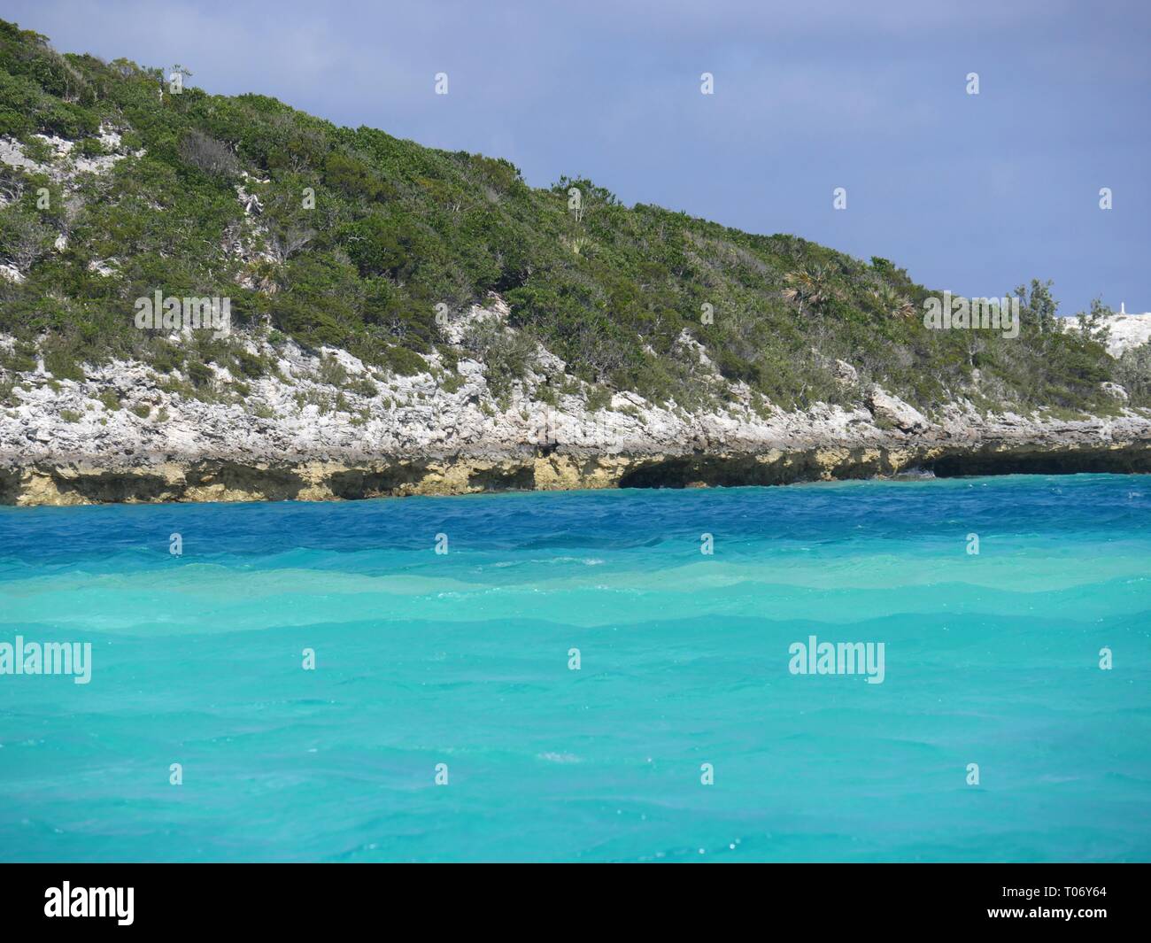 Rocky island covered in lush greens with the different hues of blue ...
