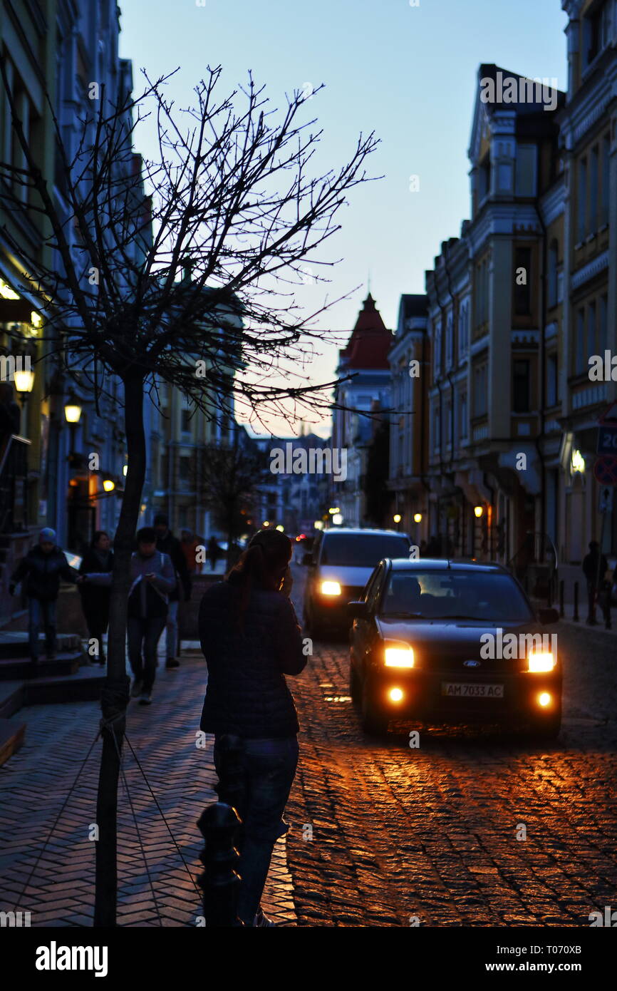 Evening lights in Kiev. Early dusk on narrow urban street with cars ...