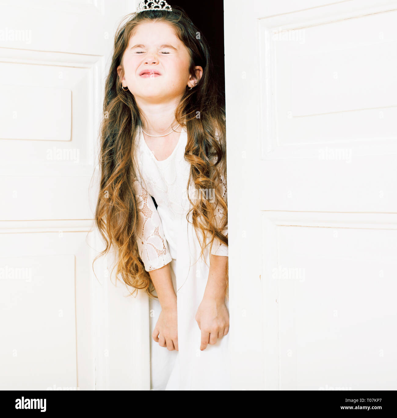 little cute girl at home, opening door well-dressed in white dress and ...