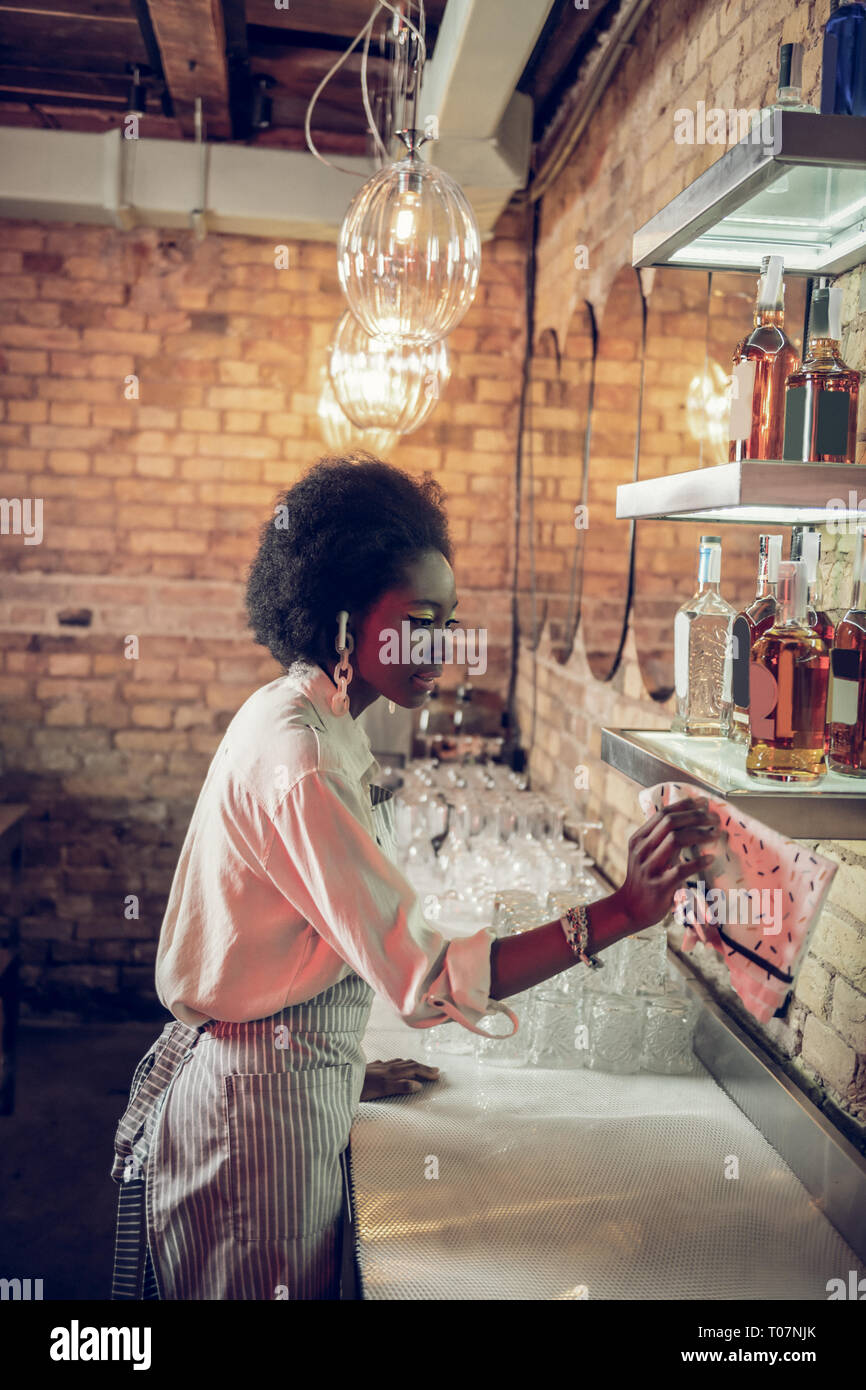 Charming female wearing white shirt doing cleaning in pub Stock Photo ...