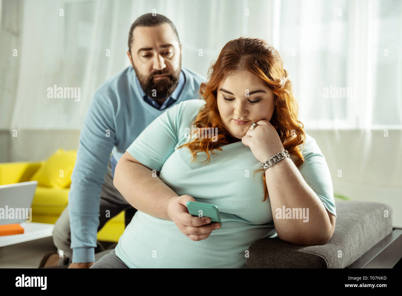 Attentive plump girl staring at screen of her gadget Stock Photo - Alamy