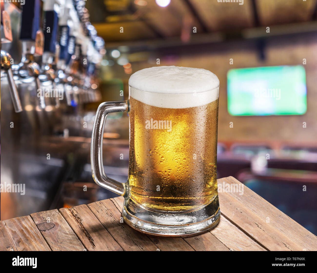 Frosty mug of light beer on the old wooden table. Pub interior and bar ...
