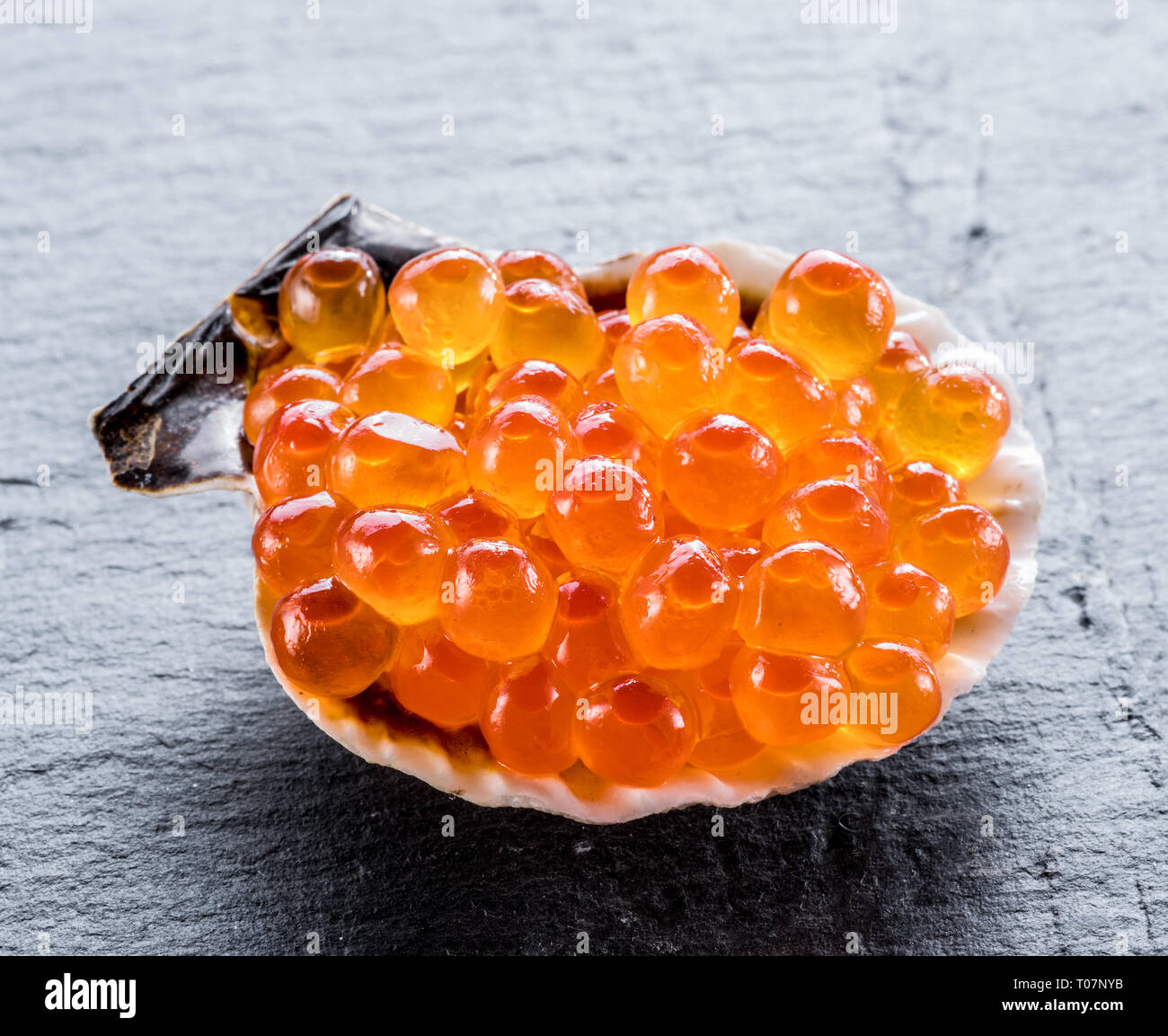 Red caviar in the sea shell on gray graphite background. Macro picture ...
