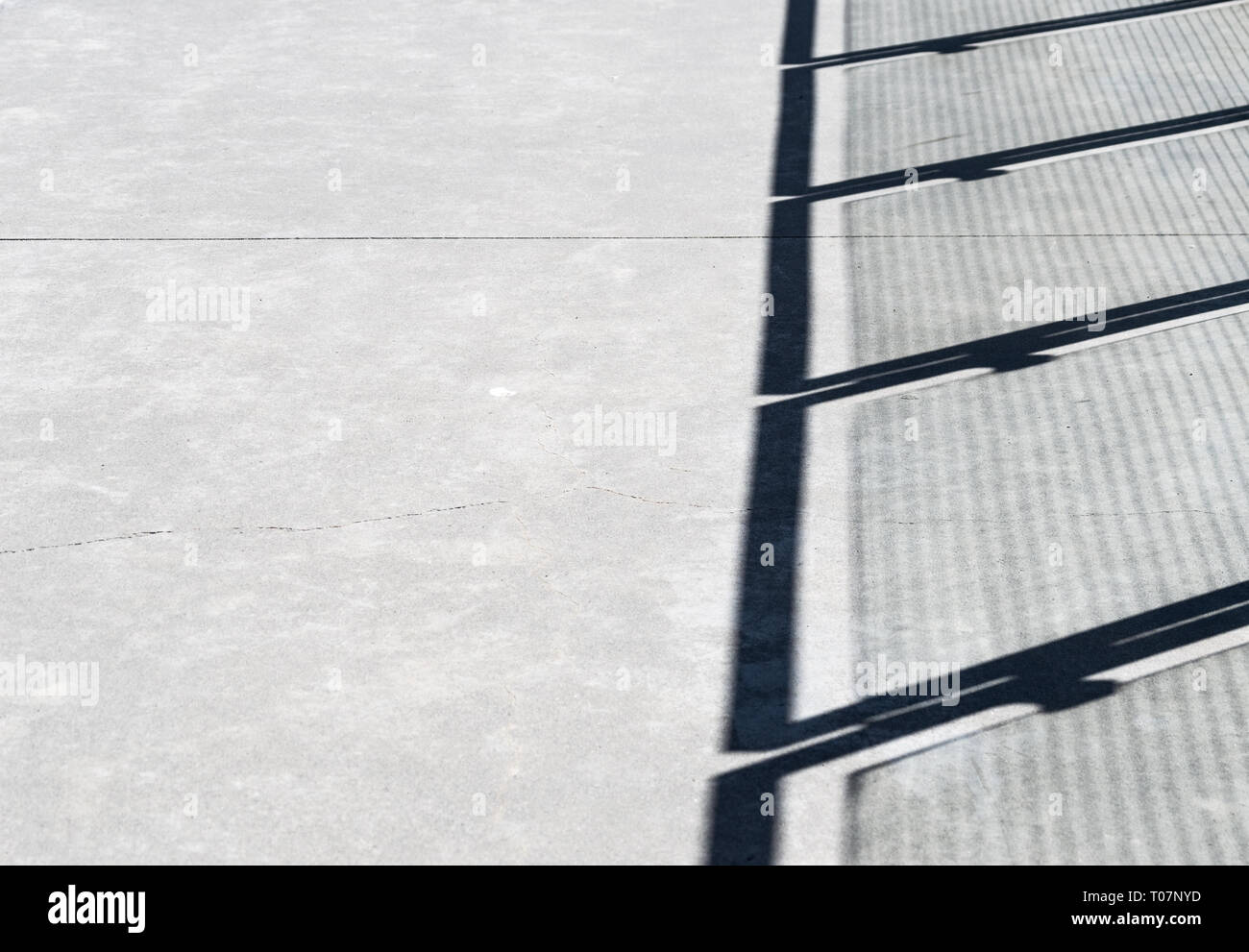 Diagonal shadows and wire mesh pattern on cement walkway from metal and ...