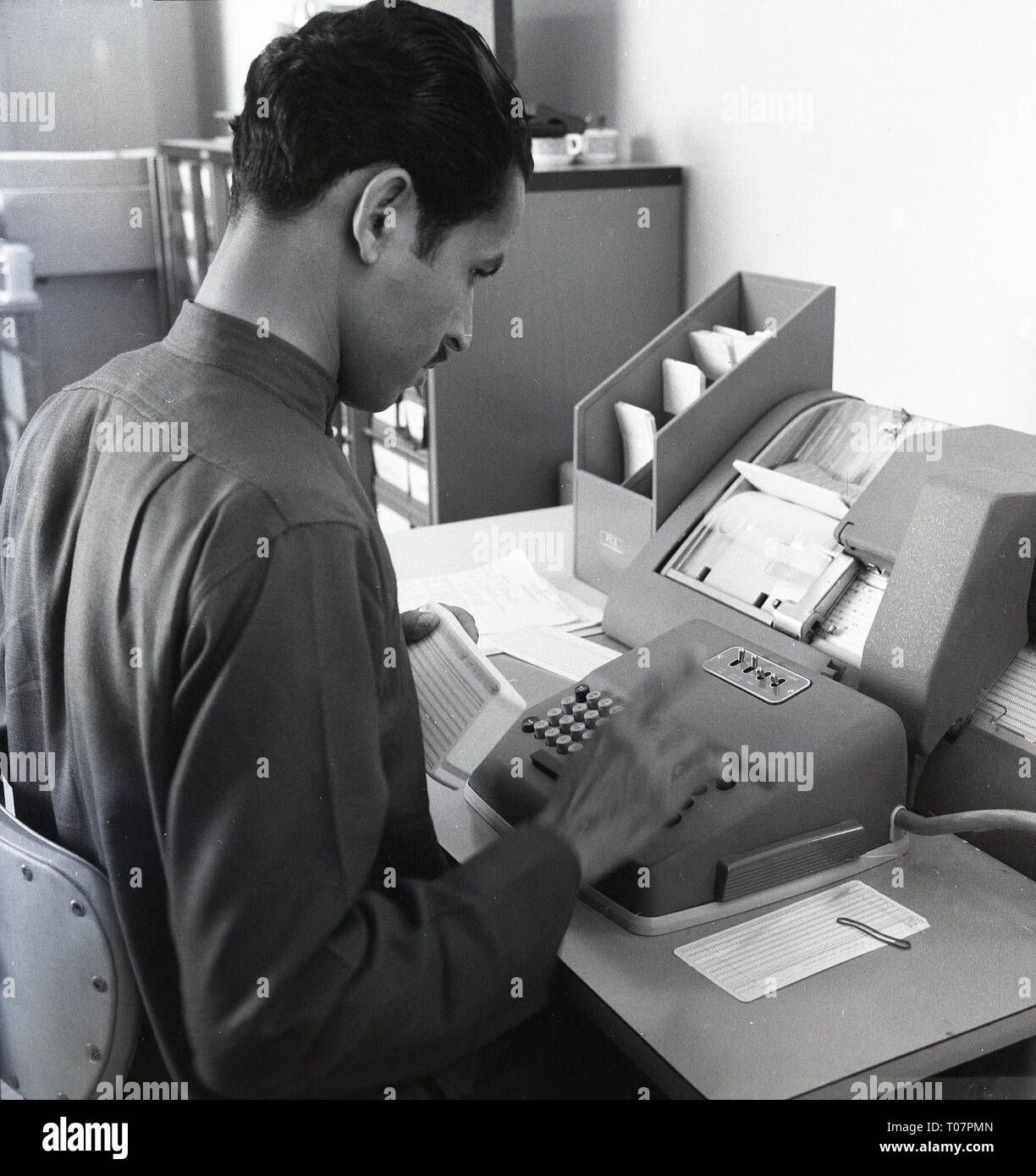 1960s, data processing, Arab man sitting at a desk using electronic ...
