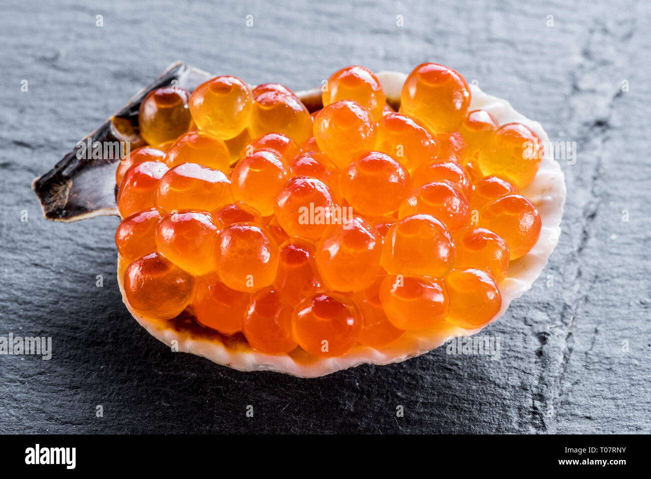 Red caviar in the sea shell on gray graphite background. Macro picture ...