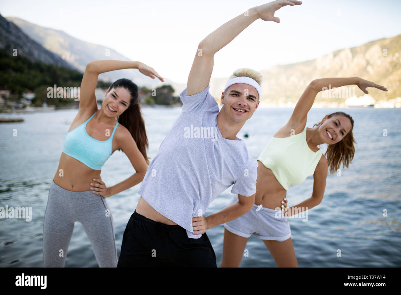 Group of happy friends or sportsmen exercising and stretching outdoor ...